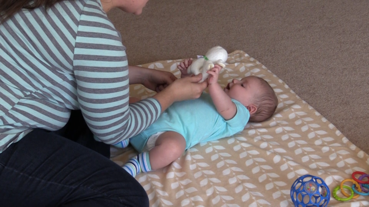 Pathways.org | While lying on back, attempts to reach for a toy held above their chest